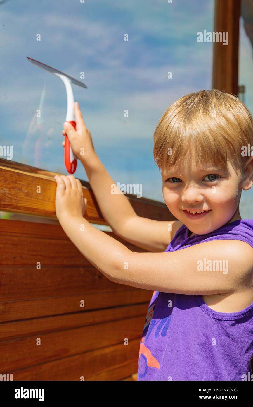 The child washes the windows with a special brush. A child with blond ...