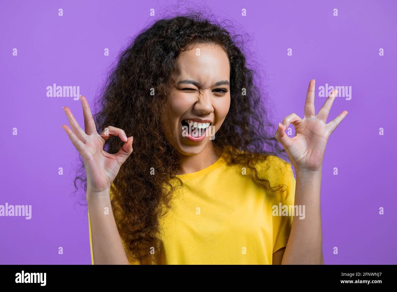Pretty woman showing ok, okay sign over purple studio background ...