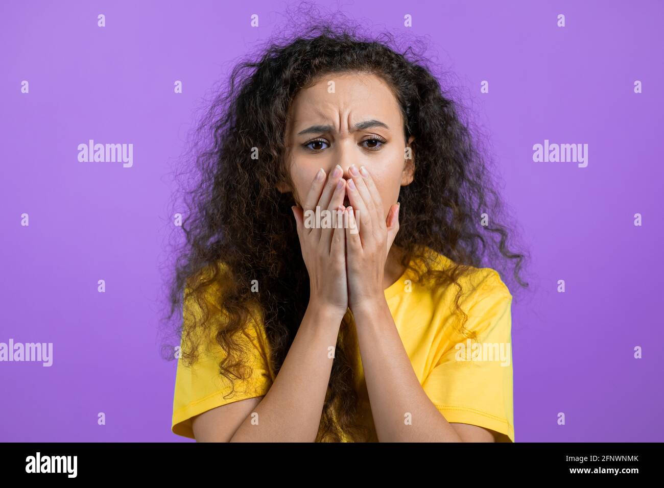 Unpleasantly surprised and shocked girl on violet studio background ...