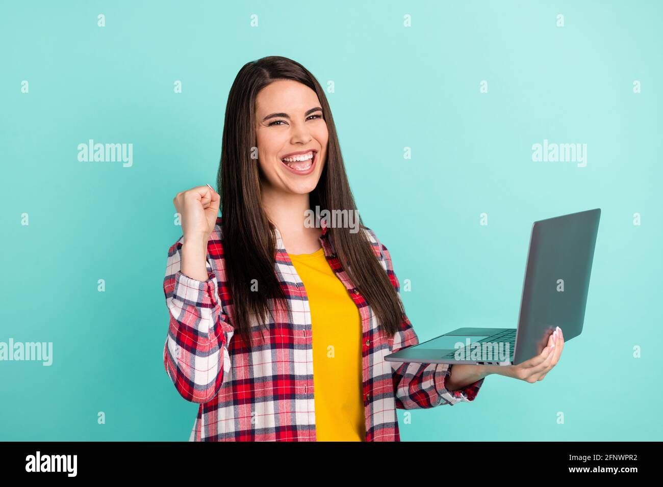 Photo of cheerful victorious young woman raise fist hold computer ...