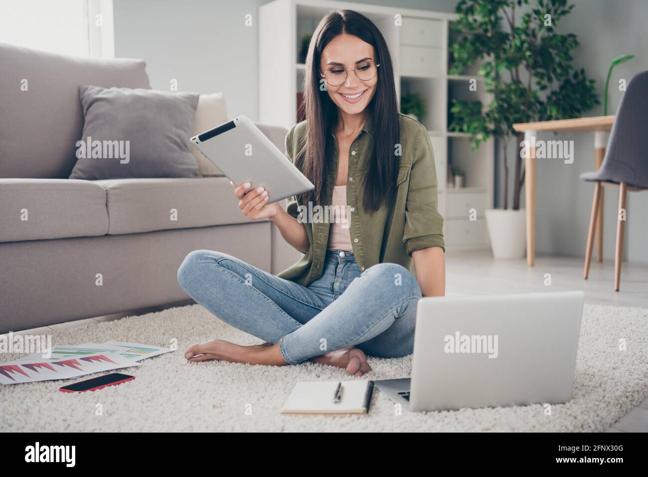 Full body portrait of charming cheerful person sit on floor hold tablet ...