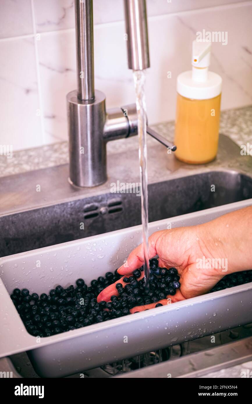 Person hand washing blueberries in kitchen sink. Close-up Stock Photo ...
