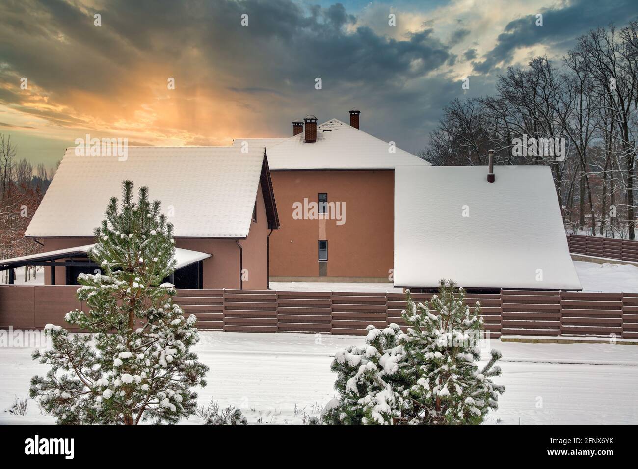residential country cottage under the snow in the forest at sunset ...