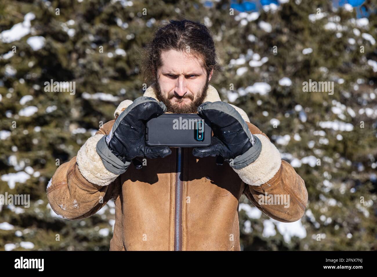 Funny and ironic portrait of a young man in a winter coat taking a ...