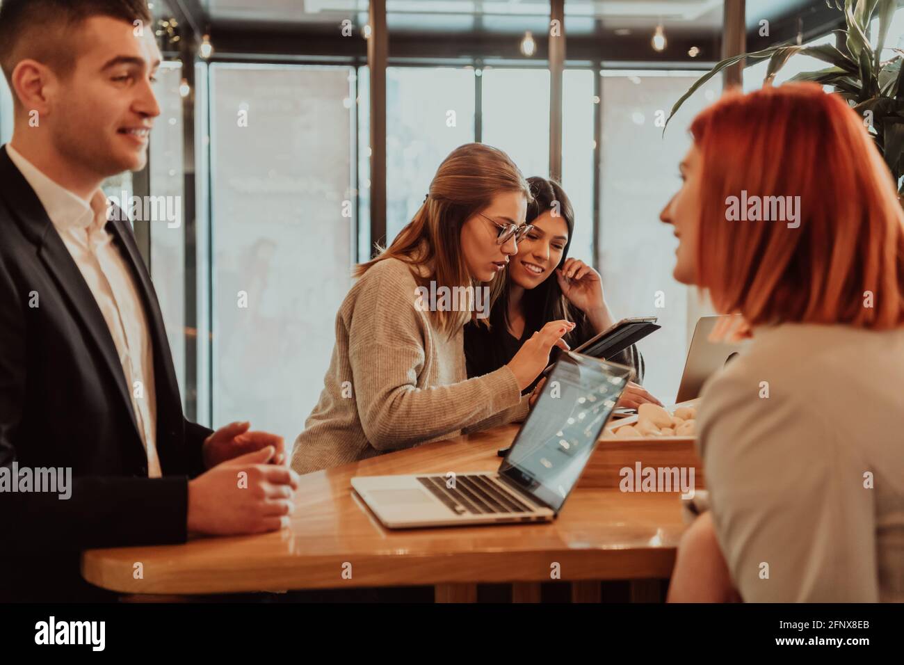 A group of friends hanging out in a cafe, and talking about business ...