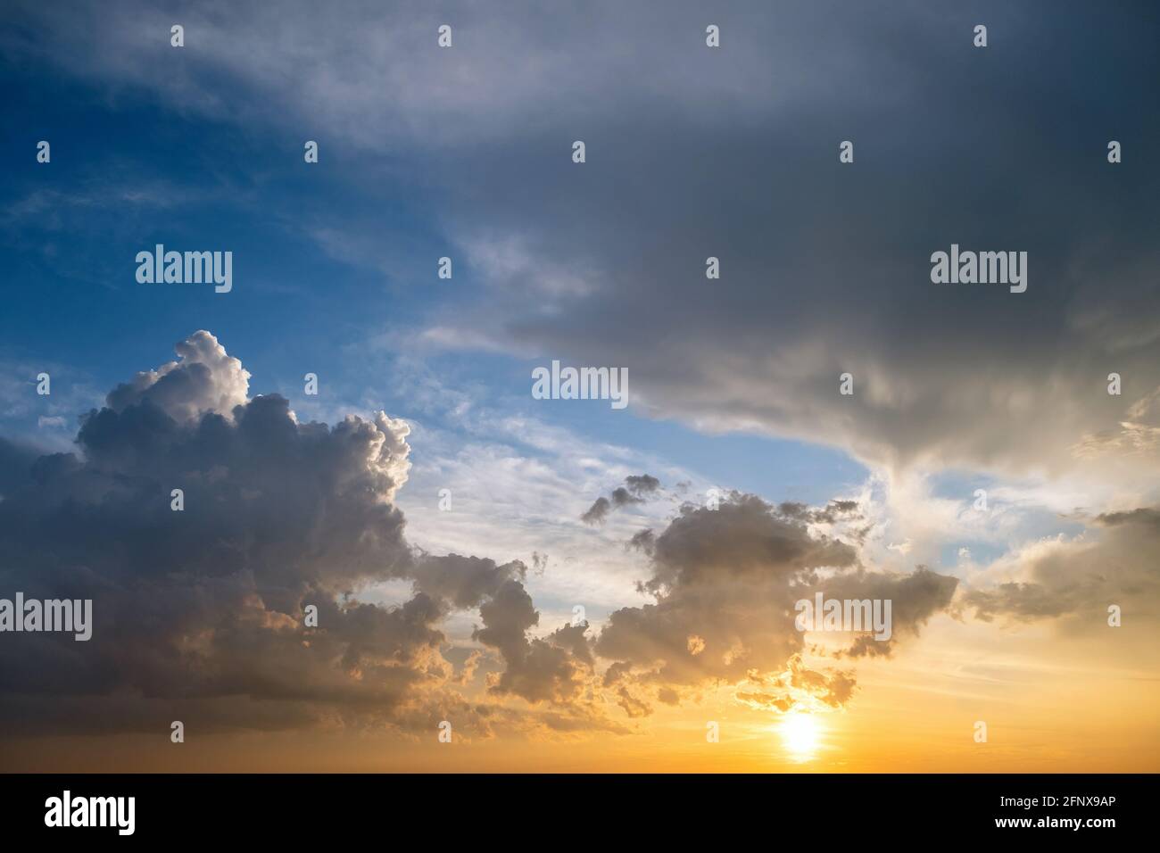 Dramatic yellow sunset landscape with puffy clouds lit by orange ...