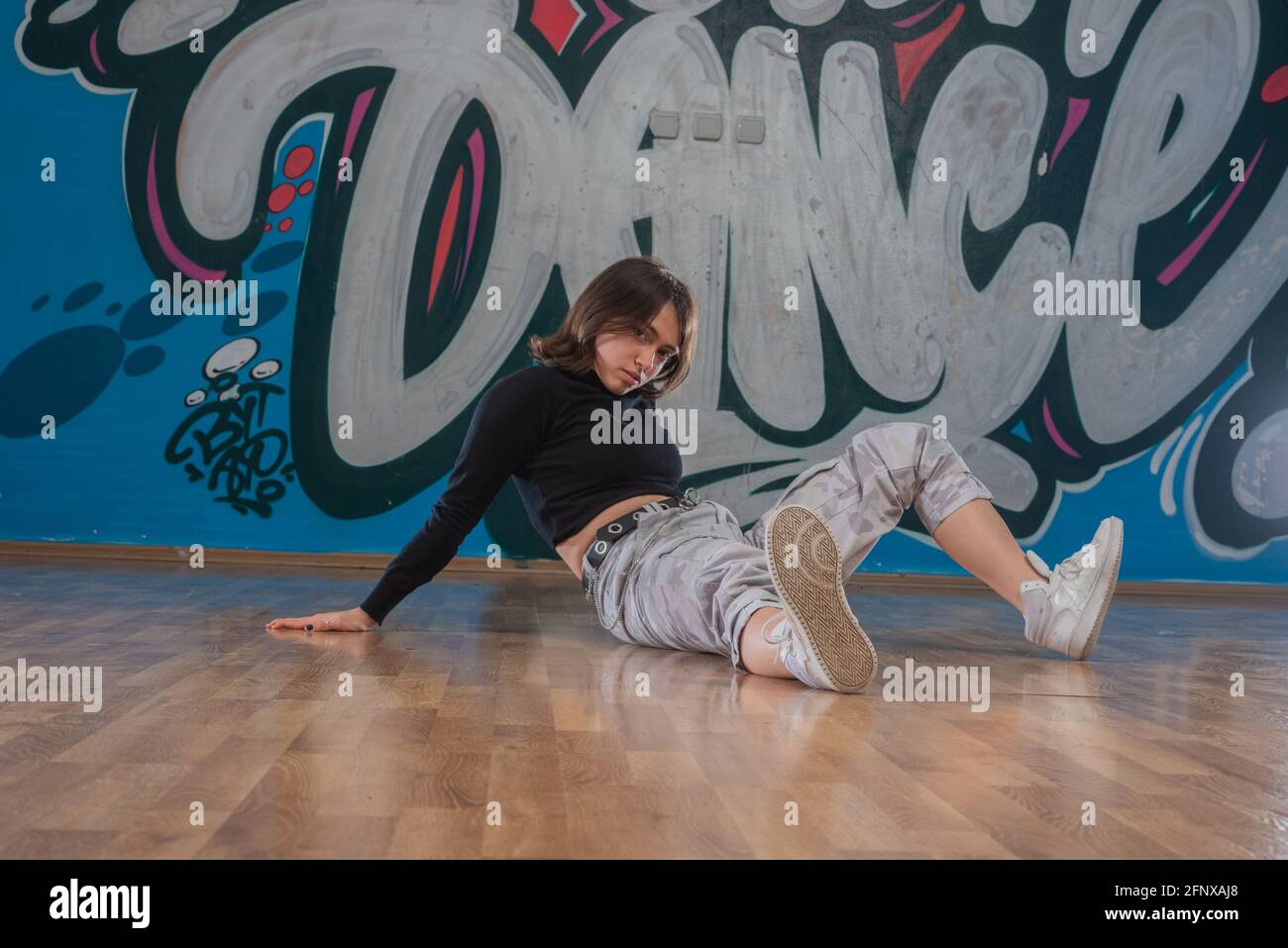 Attractive young woman doing breakdance move over graffiti background ...