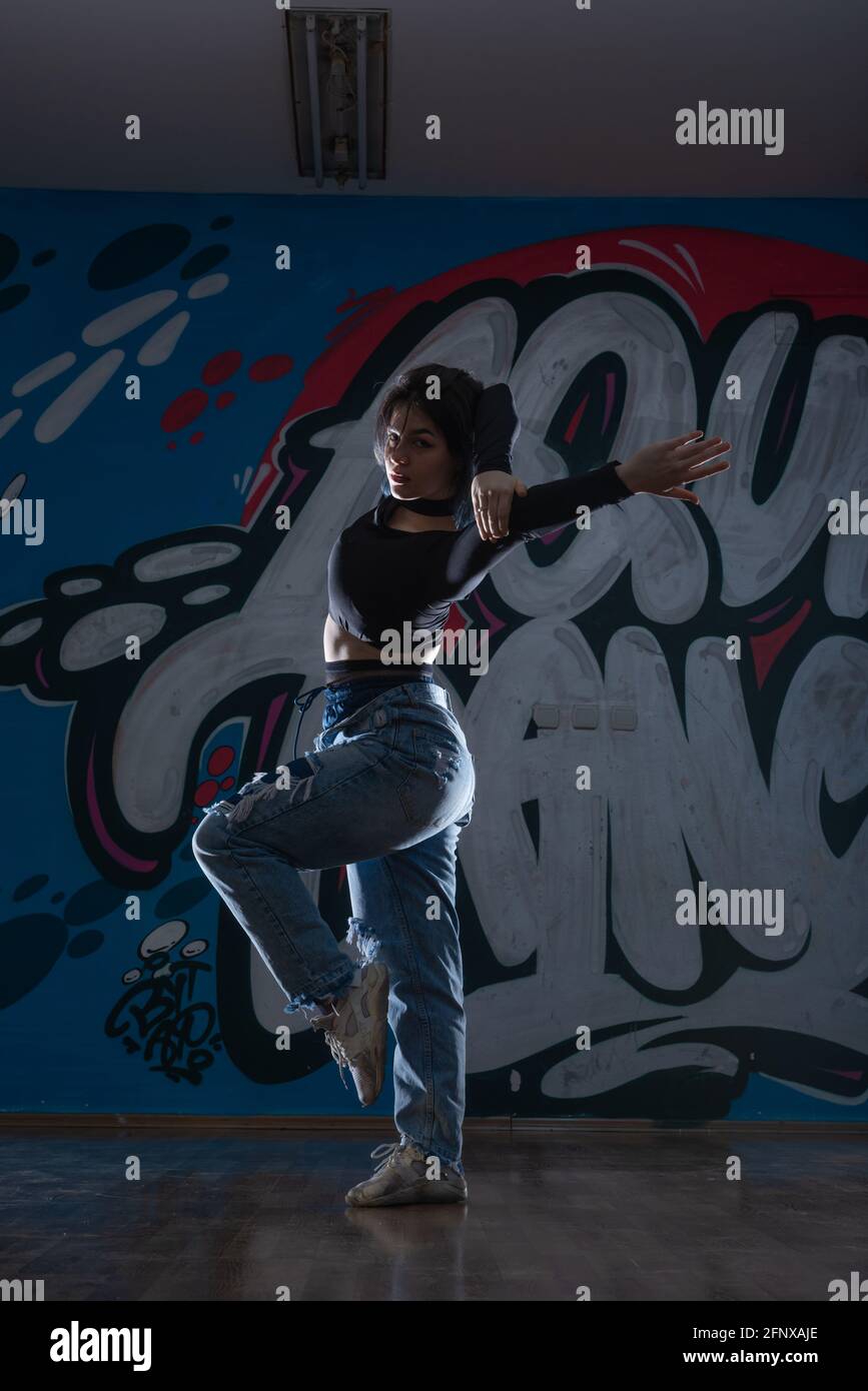 Female dancer in activewear squatting on the floor of modern dance ...