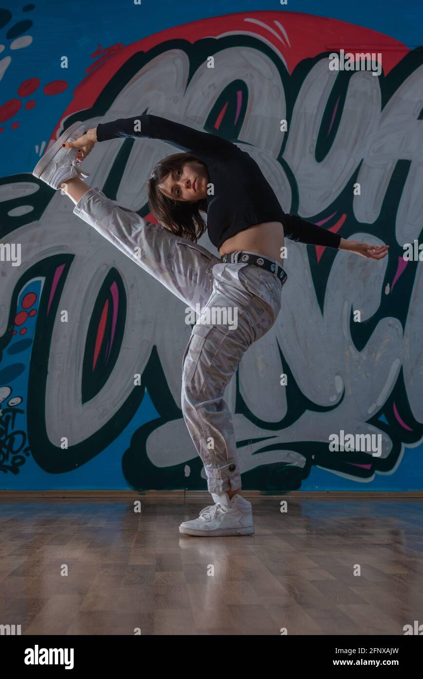 Attractive young woman doing breakdance move over graffiti background ...