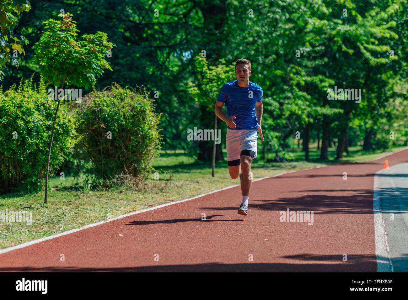 Handsome man jogging during sunny morning out on the race track Stock ...