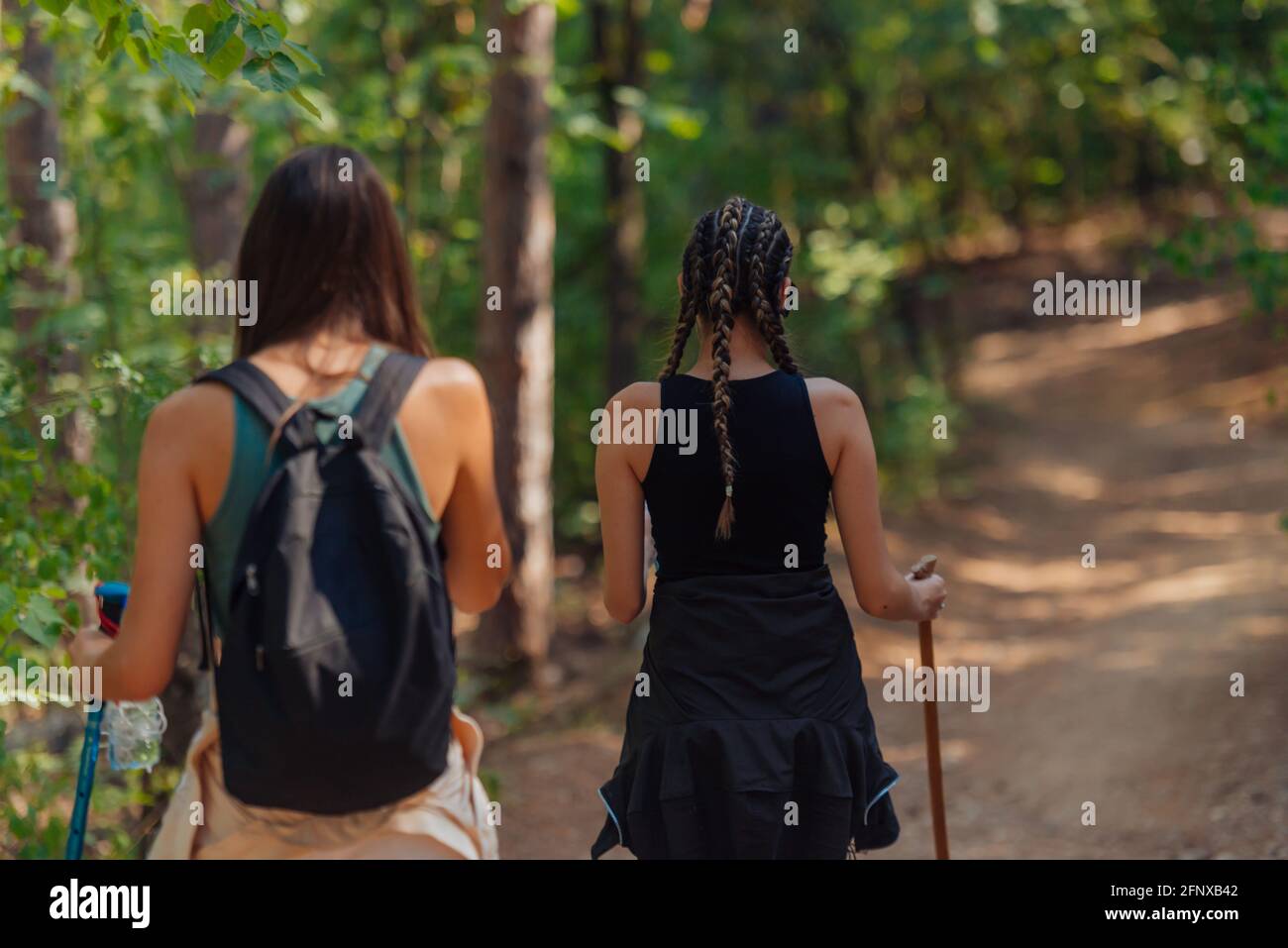 Sisters hiking through beautiful woods while wearing a backpack and ...