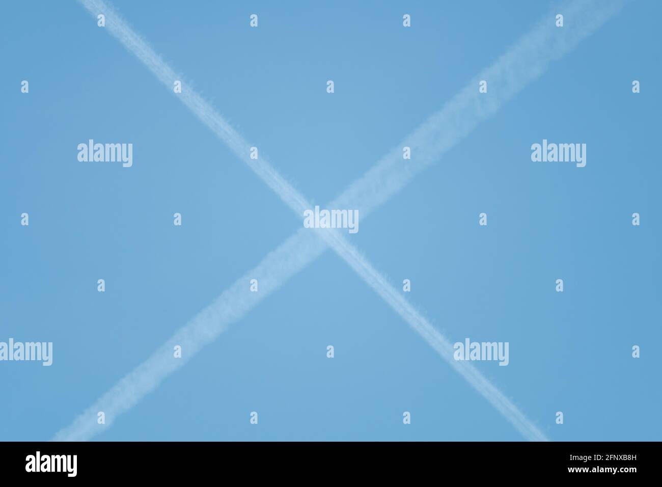 crossing of plane trails in the blue sky forming an "X Stock Photo - Alamy