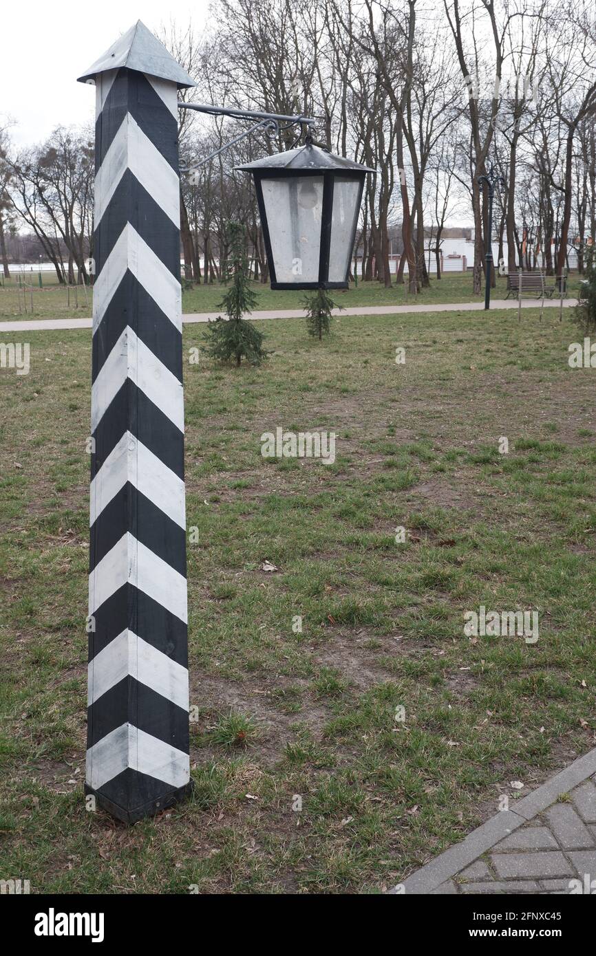 Sculpture of an old border pillar in black and white stripes and a ...