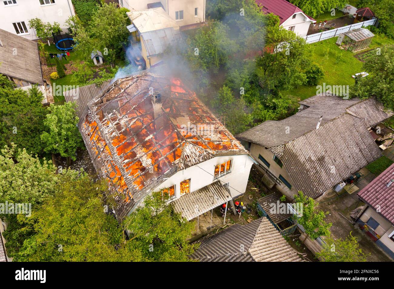 Aerial view of a house on fire with orange flames and white thick smoke ...