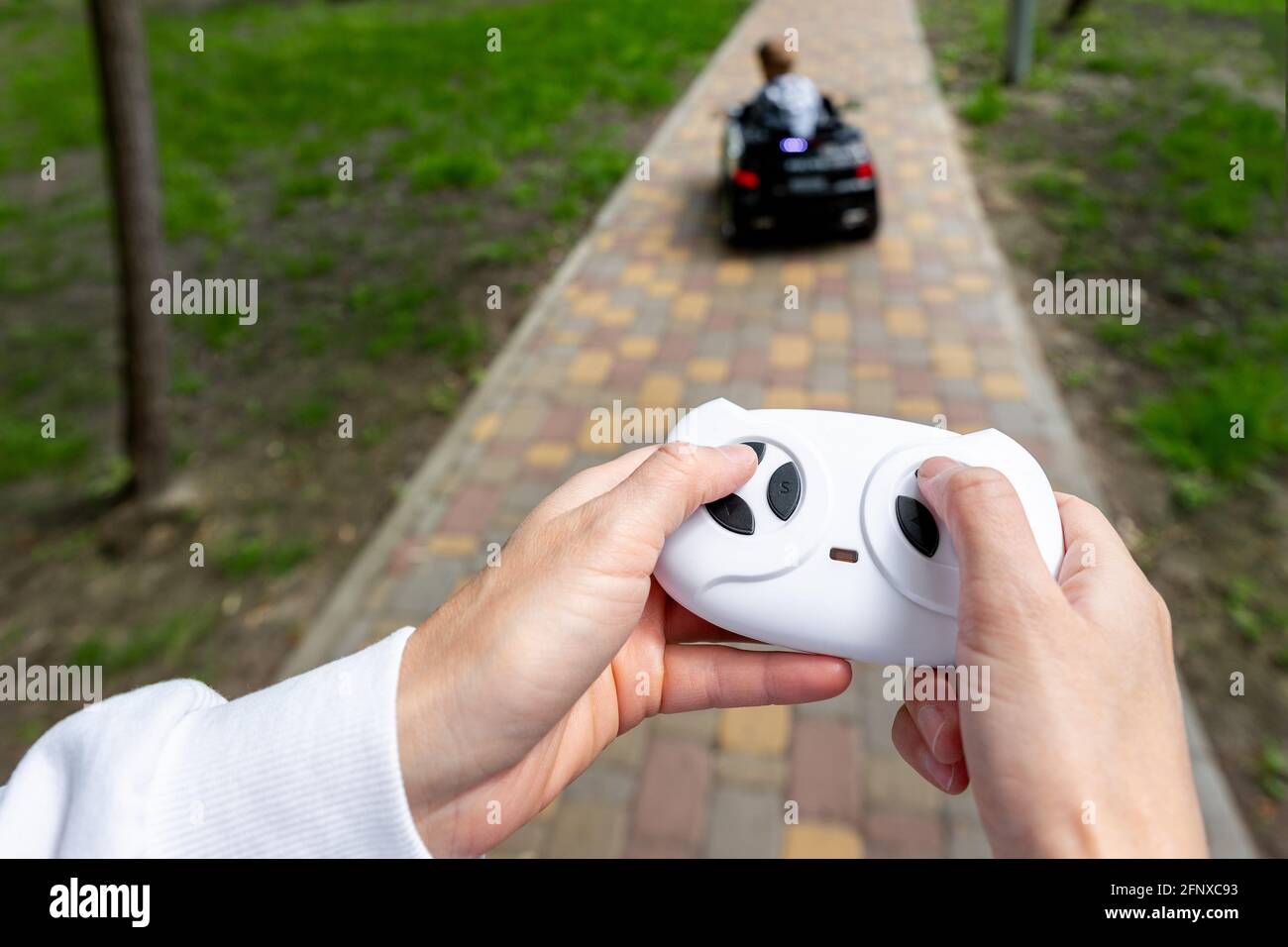 Parent hand holding remote controller of electric powered battery car ...