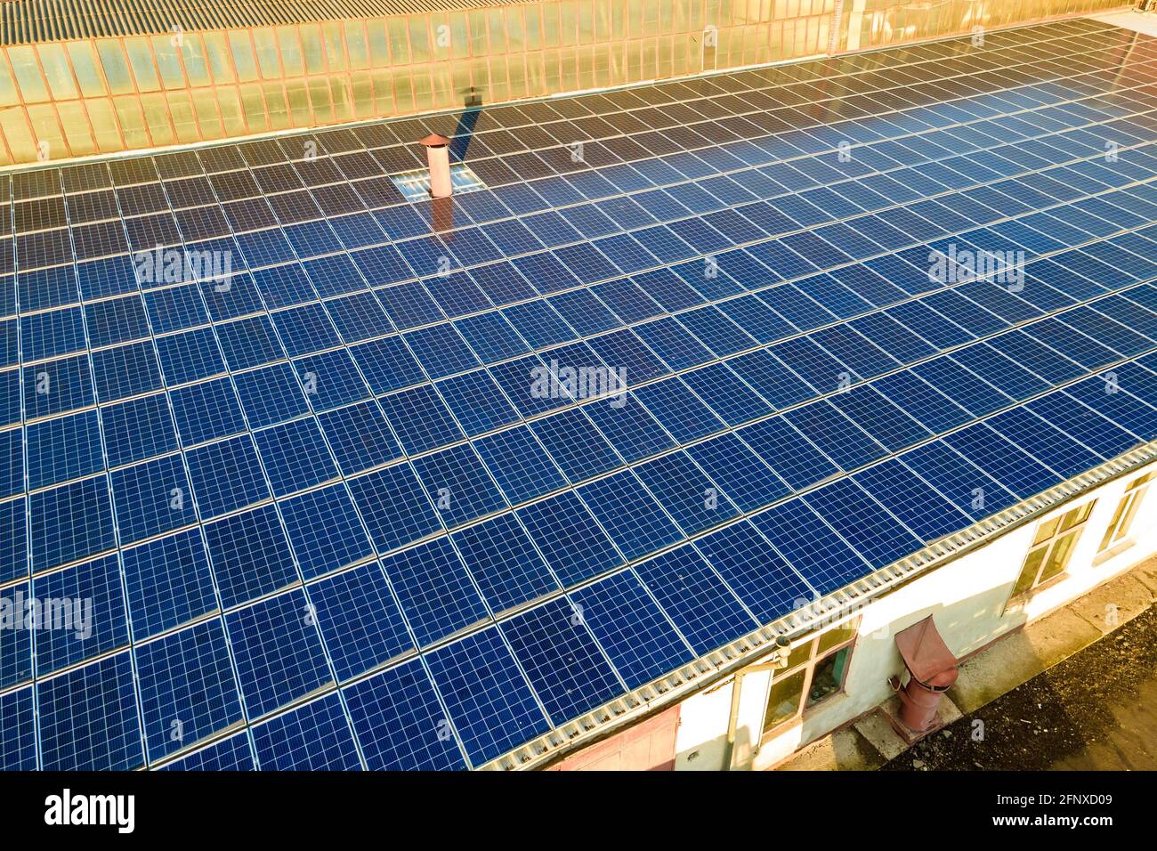 Blue photovoltaic solar panels mounted on industrial building roof for ...