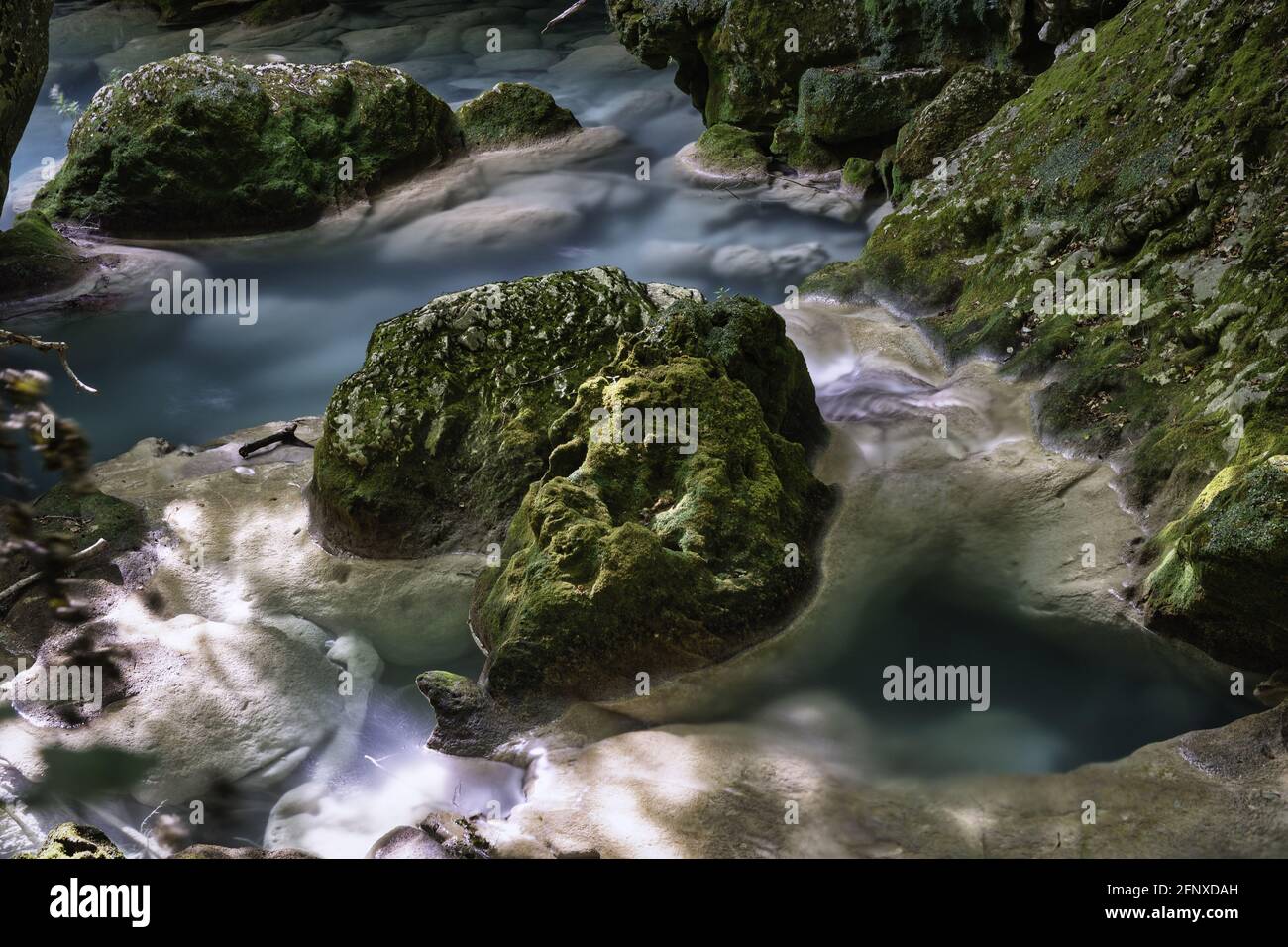 Mossy rocks in a river with turquoise water Stock Photo - Alamy