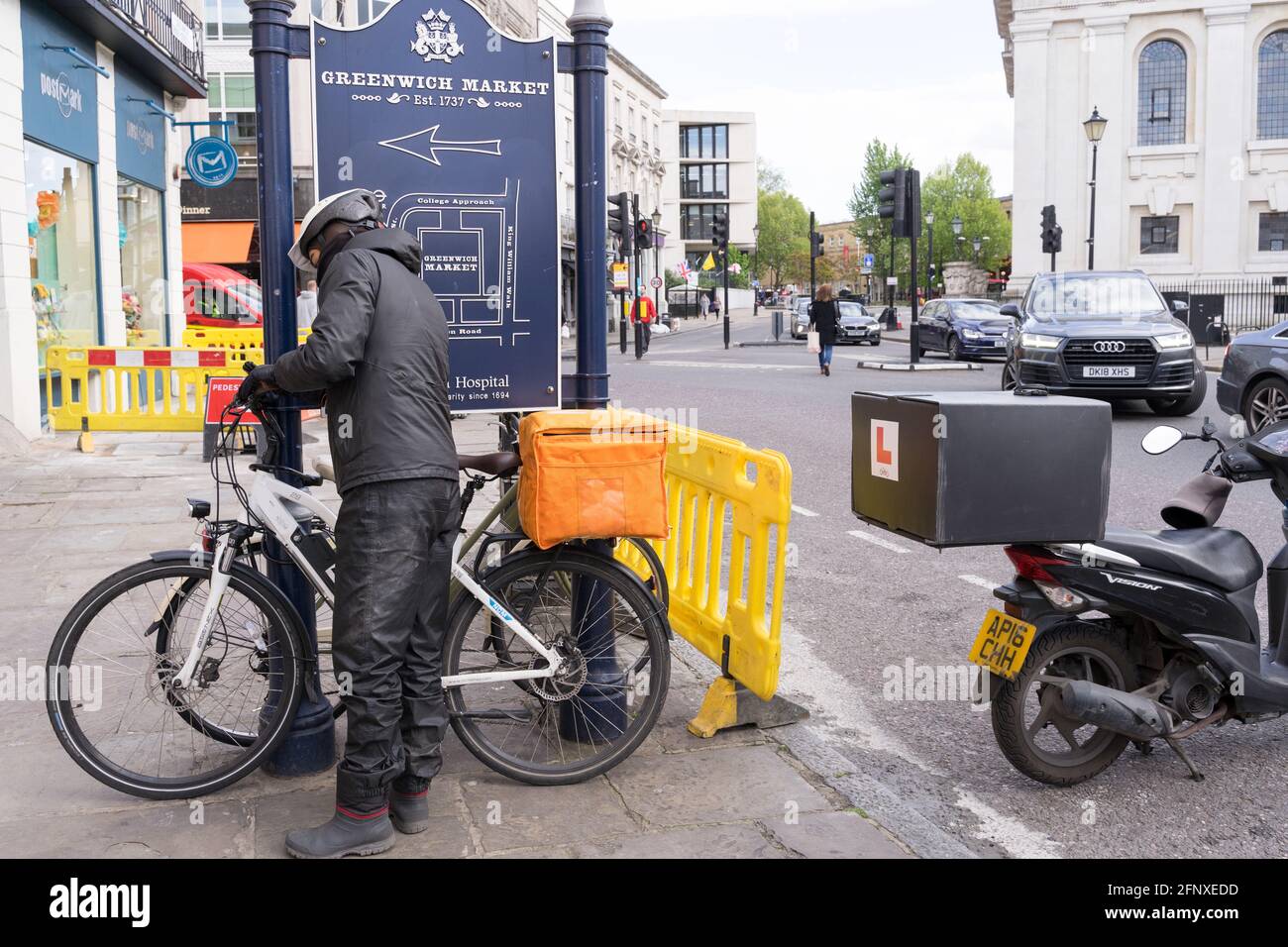 fast food delivery rider check his bike beside the sign of Greenwich ...