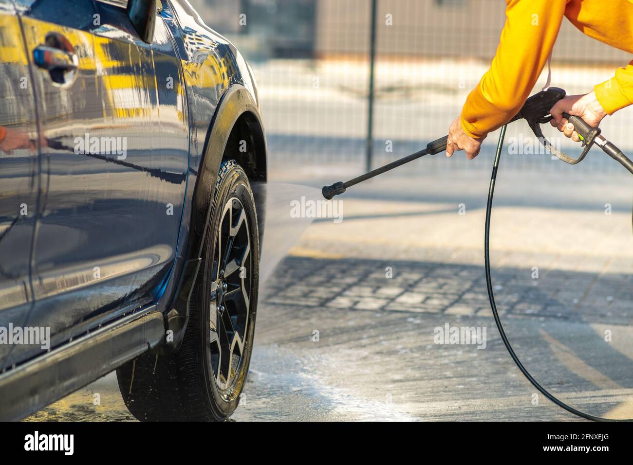 Closeup of male driver washing his car with contactless high pressure ...