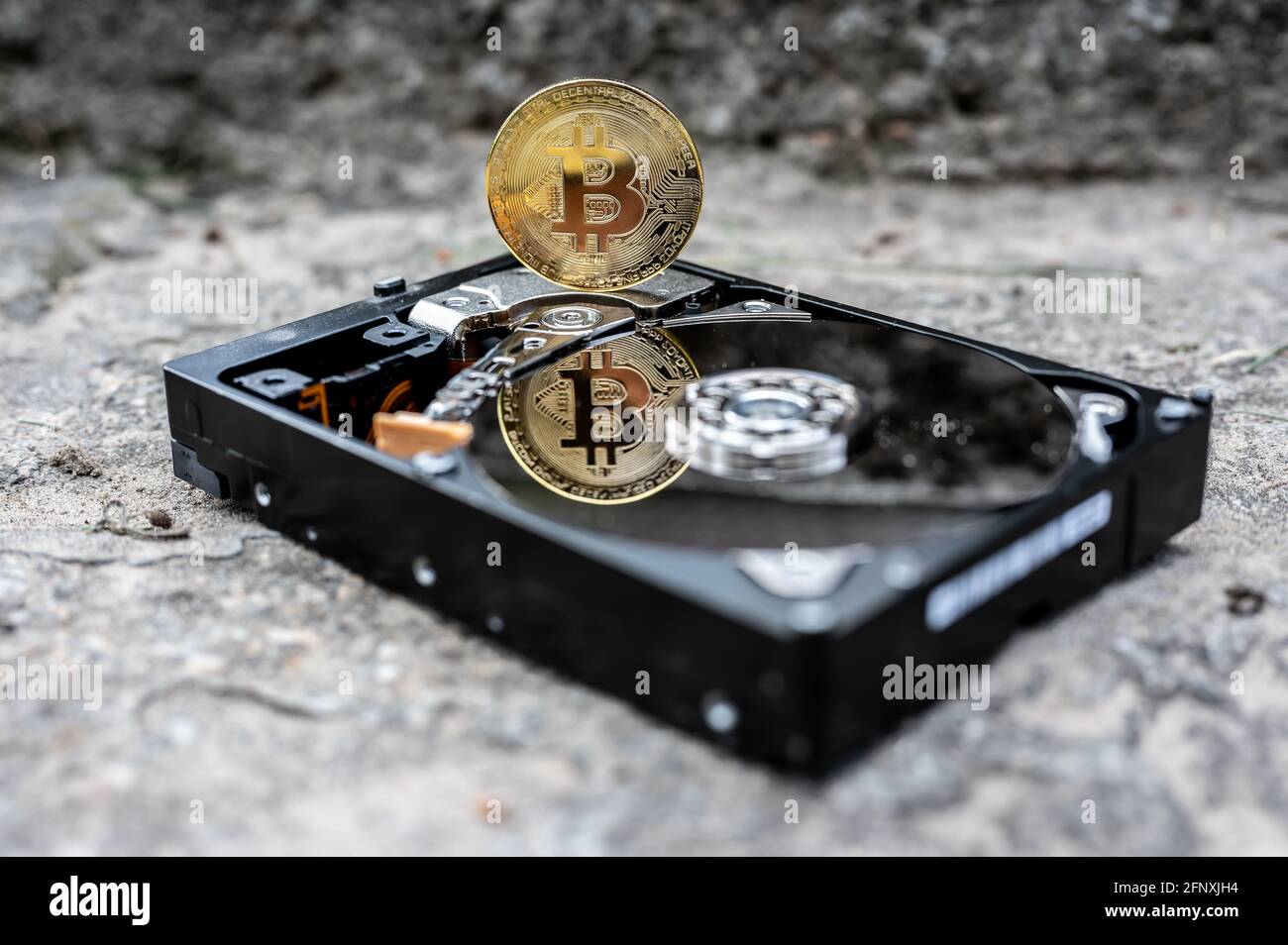 View on a hard disk drive with a bitcoin cryptocurrency on a concrete ...