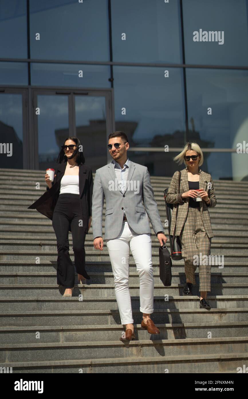 Three business partners are smiling and walking down Stock Photo - Alamy