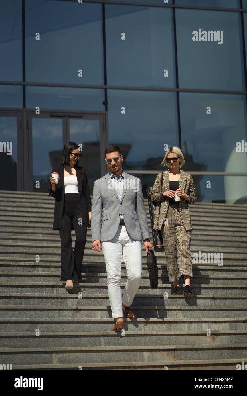 Three business partners are walking down the stairs Stock Photo - Alamy