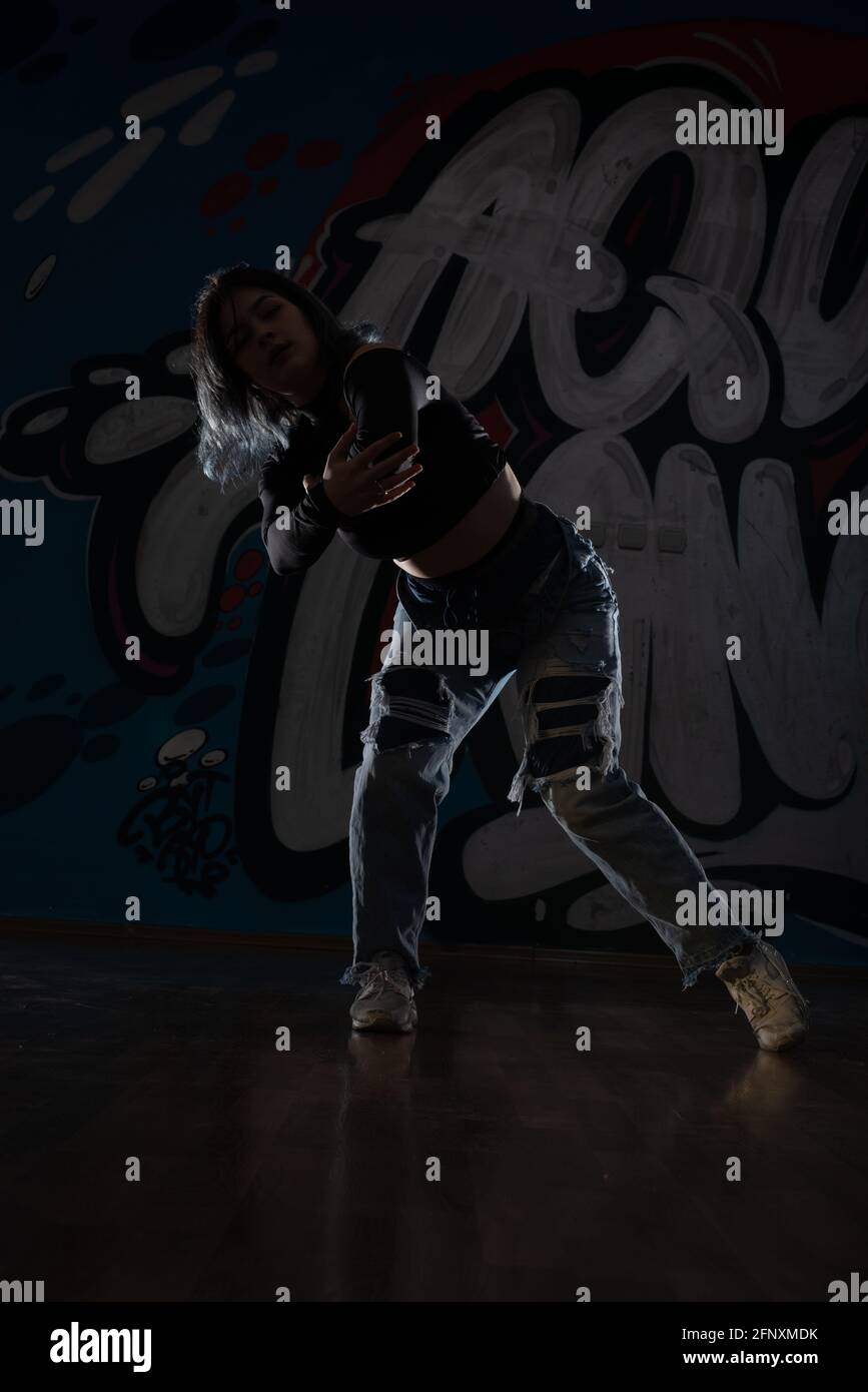 Female dancer in activewear squatting on the floor of modern dance ...