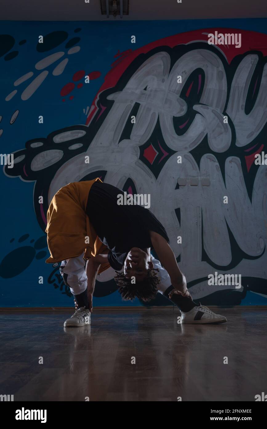 African American hip hop dancer (breakdancer) performing over graffiti ...