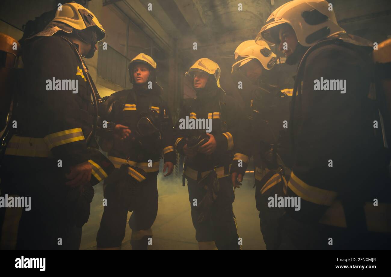Group of firefighters with uniform inside the fire station preparing ...