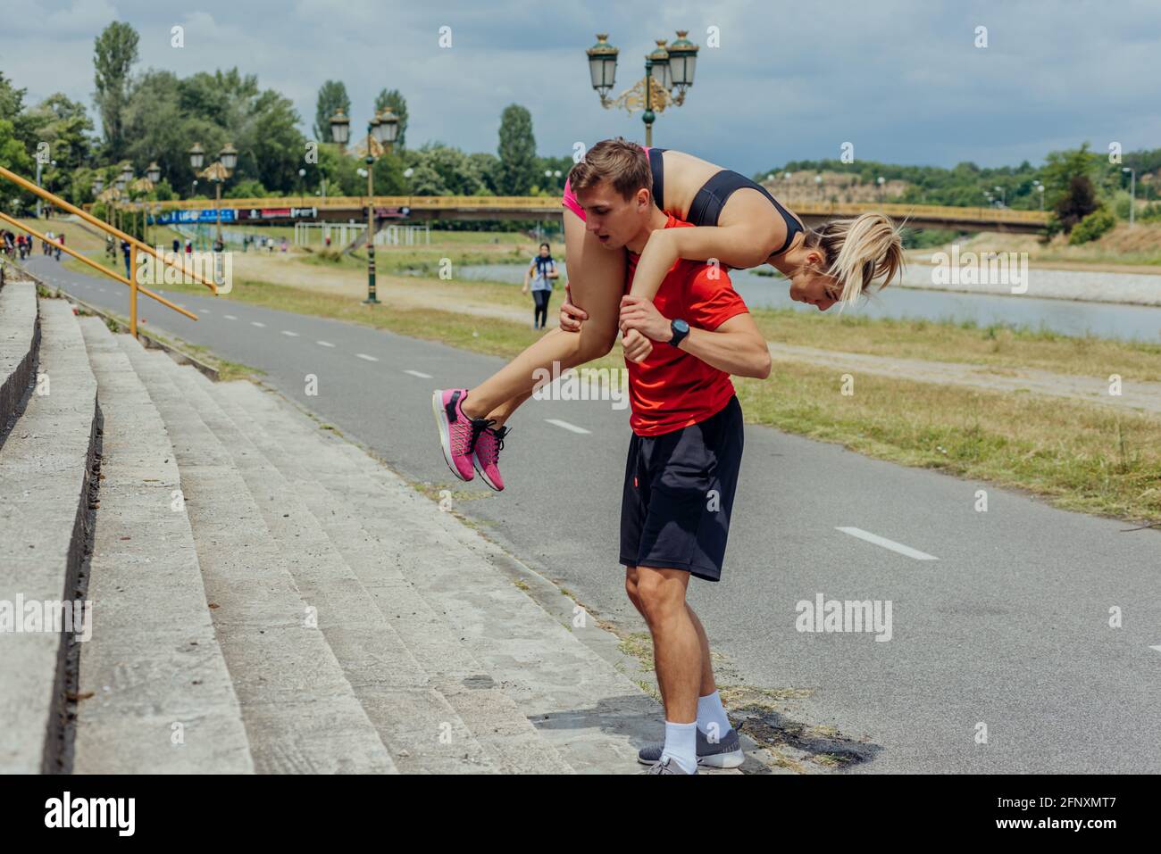 Male athlete carrying his female workout partner on his shoulders while ...