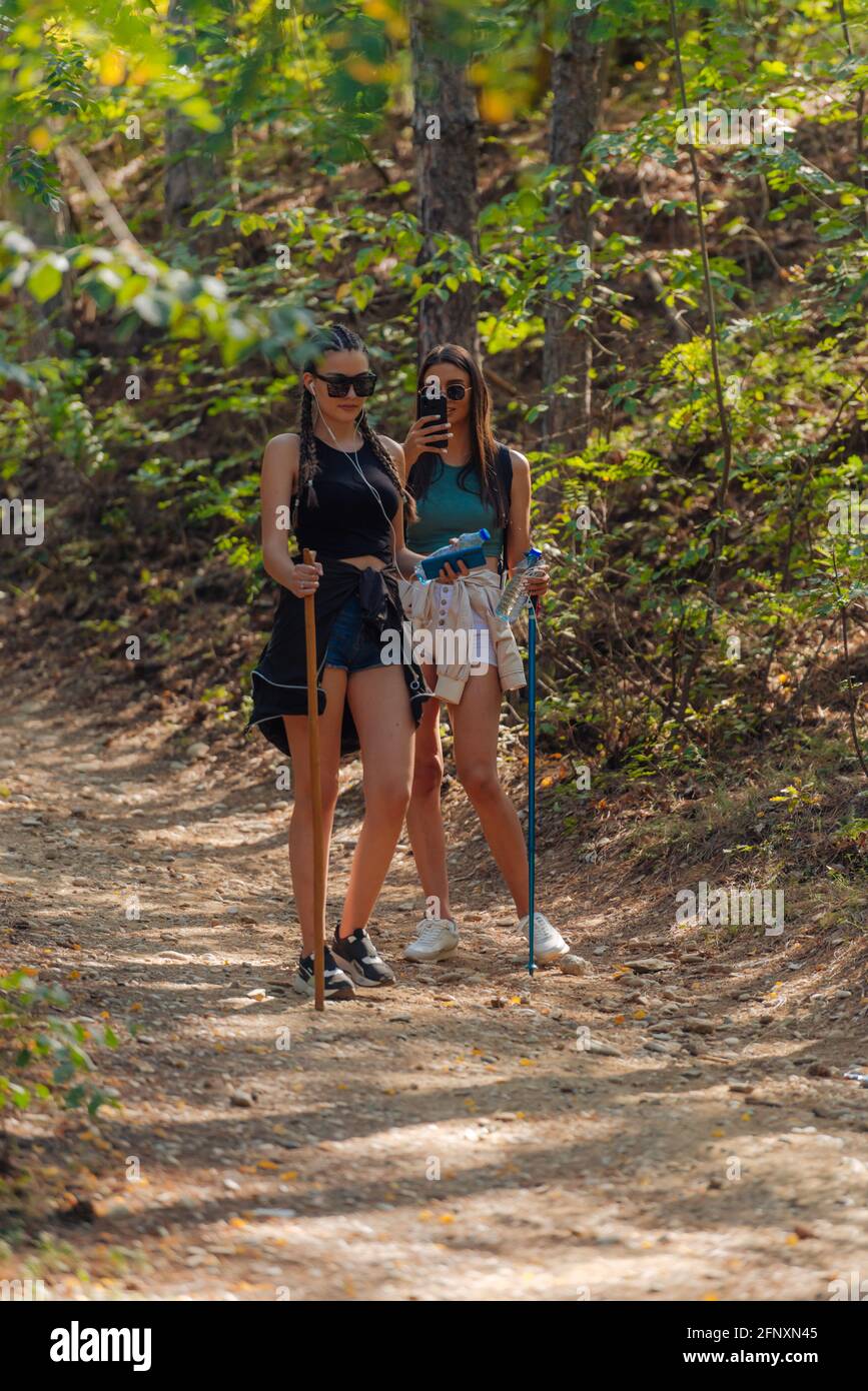 Sisters hiking through beautiful woods while wearing a backpack and ...