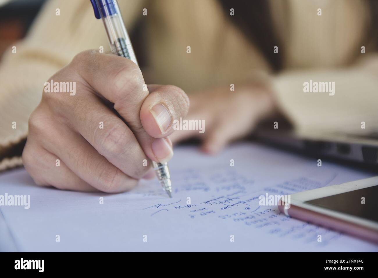 Businesswomen hand holding ballpoint pen working on laptop computer ...