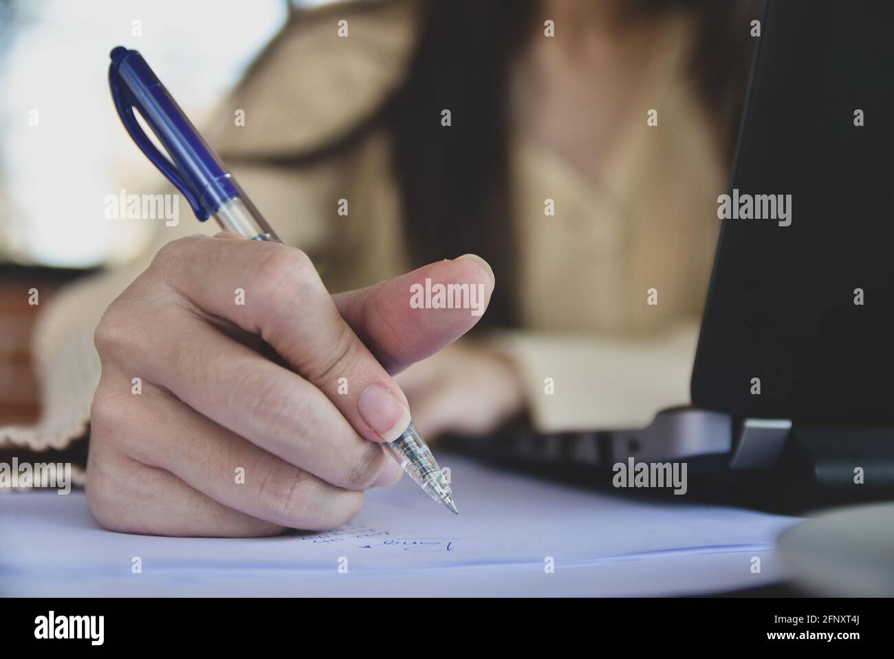 Businesswomen hand holding ballpoint pen working on laptop computer ...