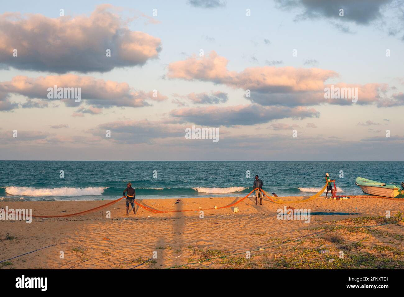Fishermen on the beach tending to their fishing nets just before sunset ...