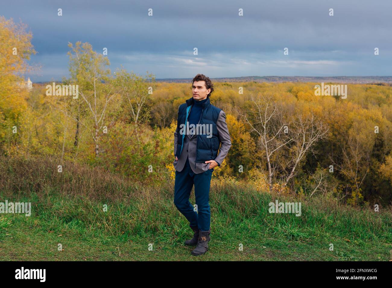 Tall handsome man walking outdoor in yellow autumn forest on the hill ...