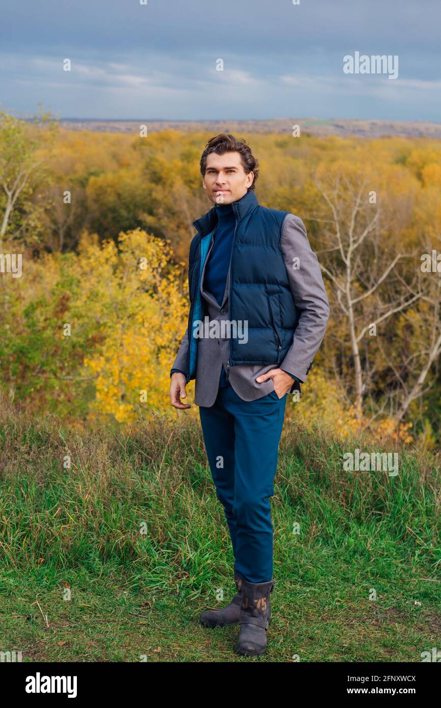 Tall handsome man walking outdoor in yellow autumn forest on the hill ...