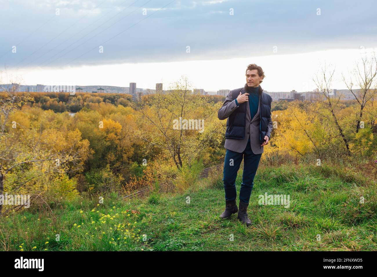 Tall handsome man walking outdoor in yellow autumn forest on the hill ...