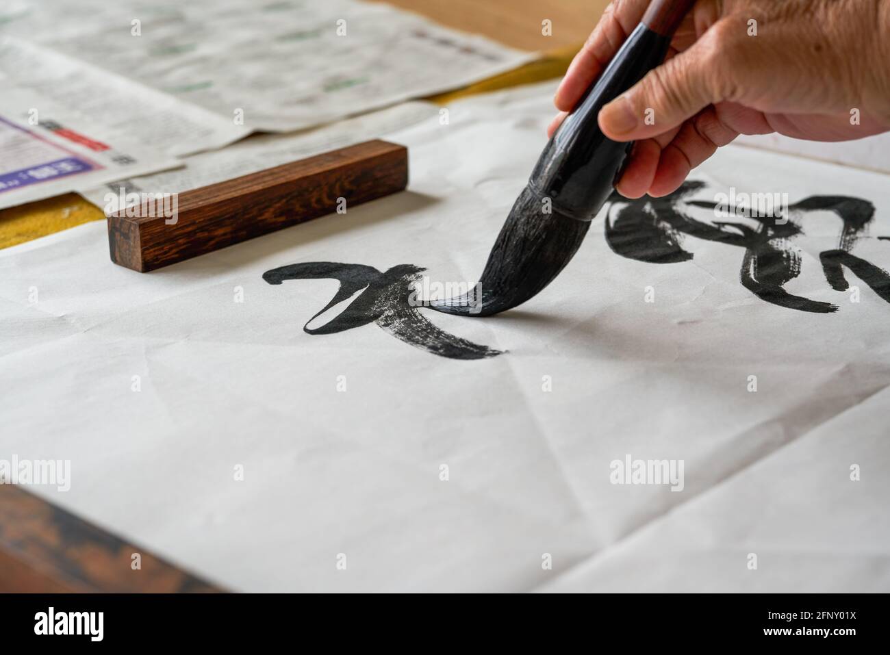 A calligrapher is writing calligraphy characters with a large brush, a ...
