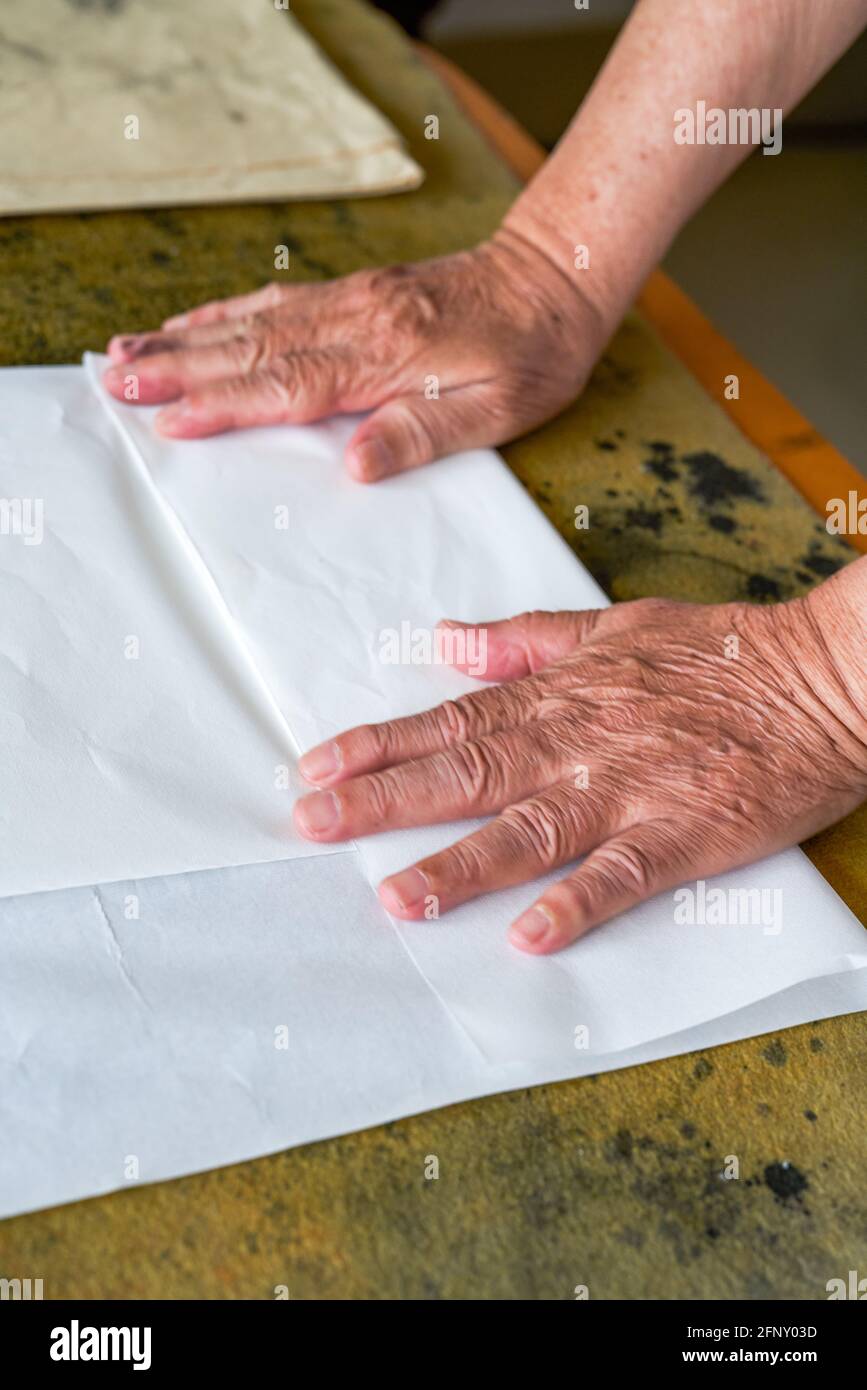 A calligrapher is folding rice paper and writing calligraphy ...