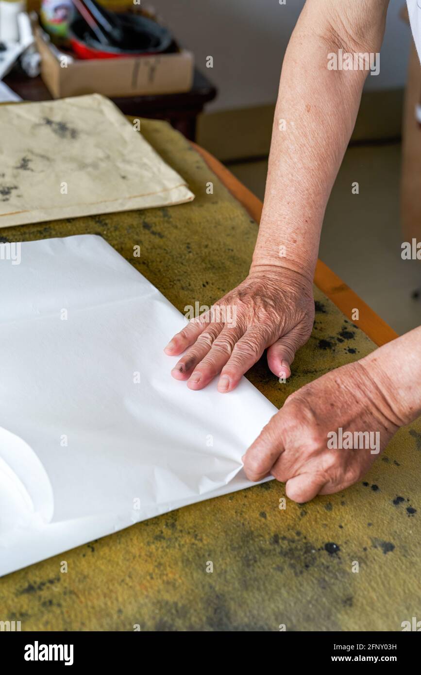 A calligrapher is folding rice paper and writing calligraphy ...