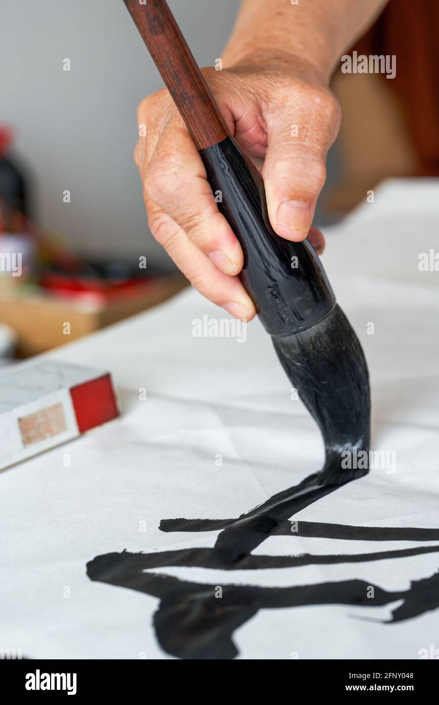 A calligrapher is writing calligraphy characters with a large brush, a ...