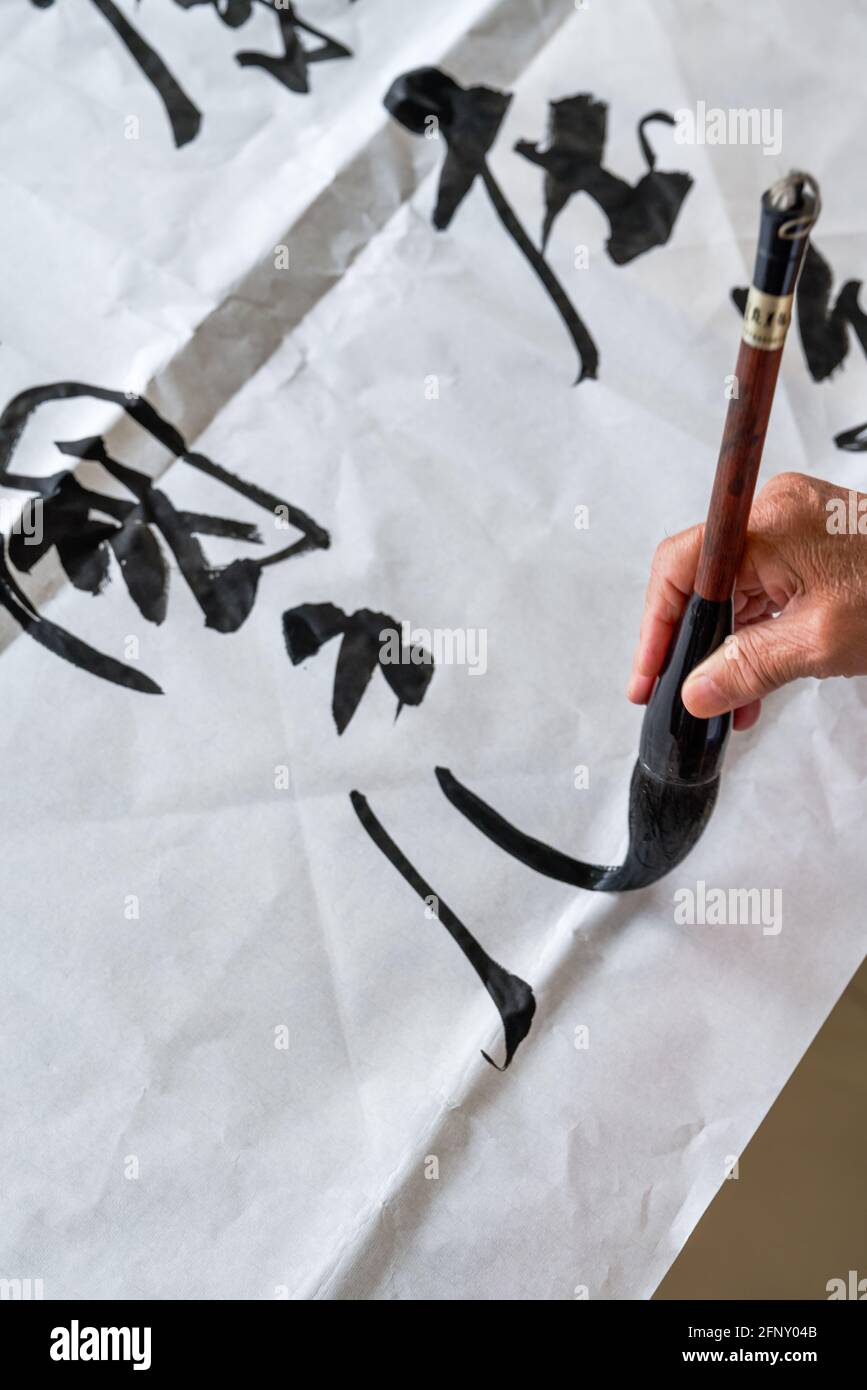A calligrapher is writing calligraphy characters with a large brush, a ...