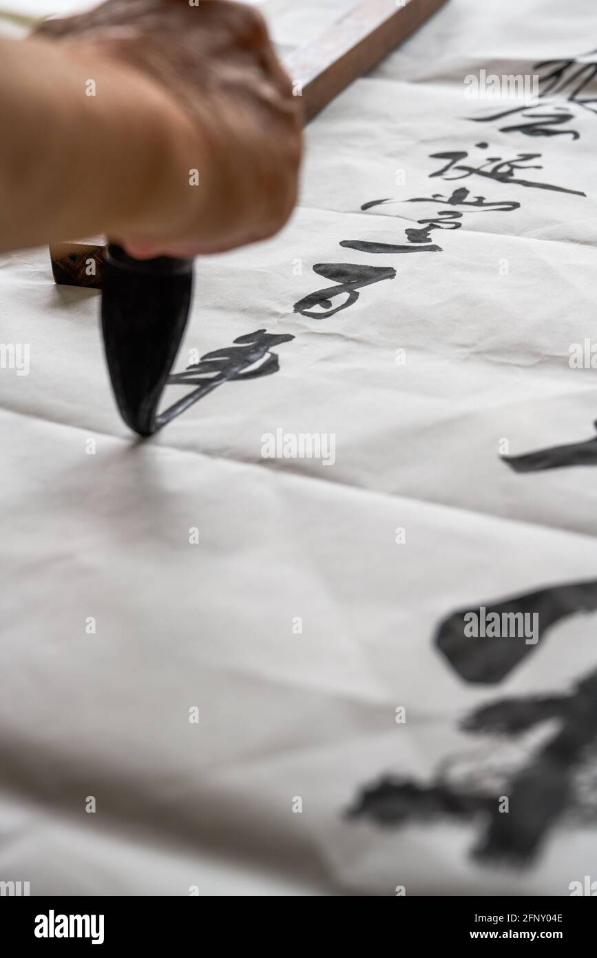 A calligrapher is writing calligraphy characters with a large brush, a ...