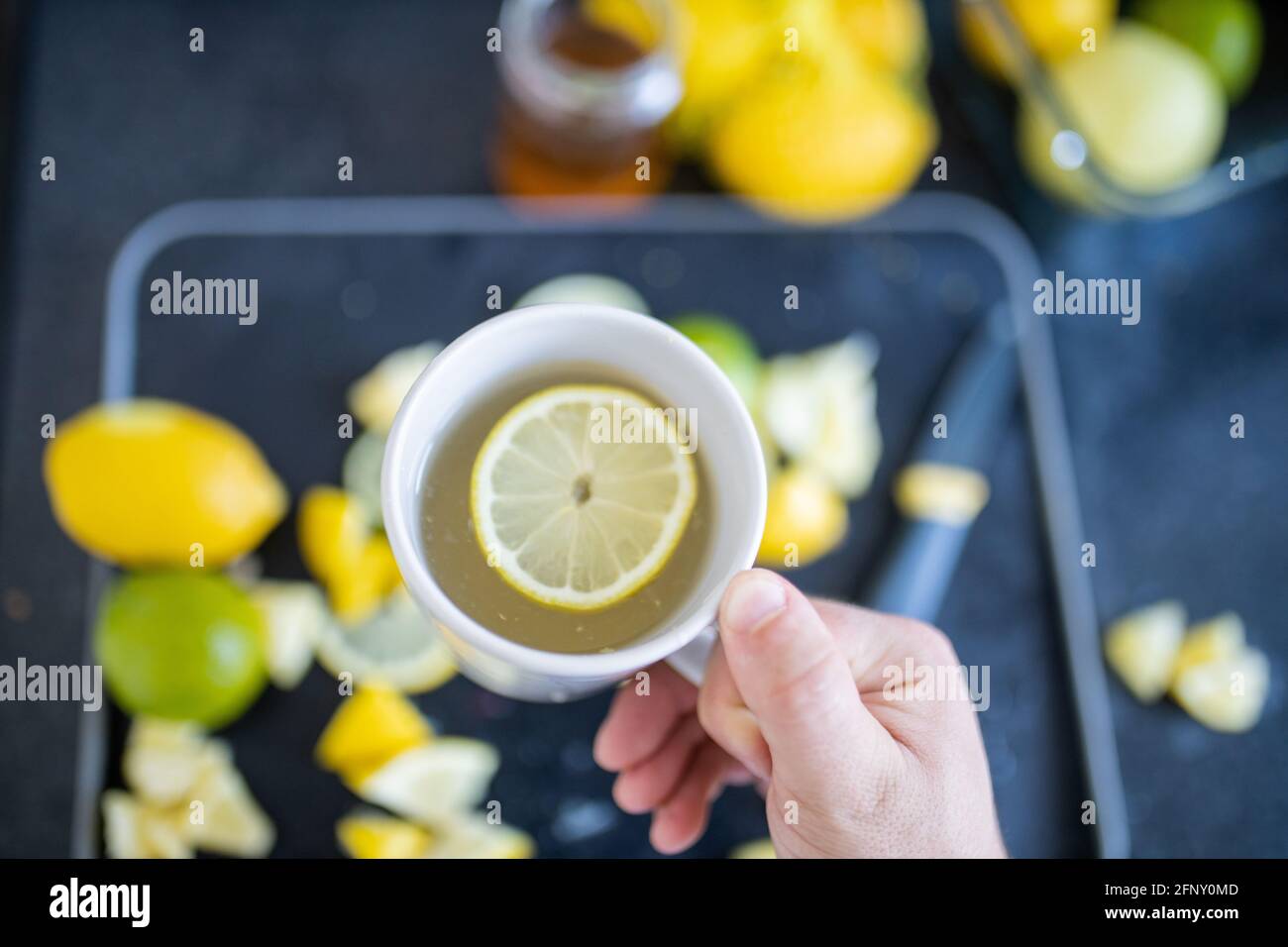 Male hand holding a cup of lemon tea above fruit slices Stock Photo - Alamy