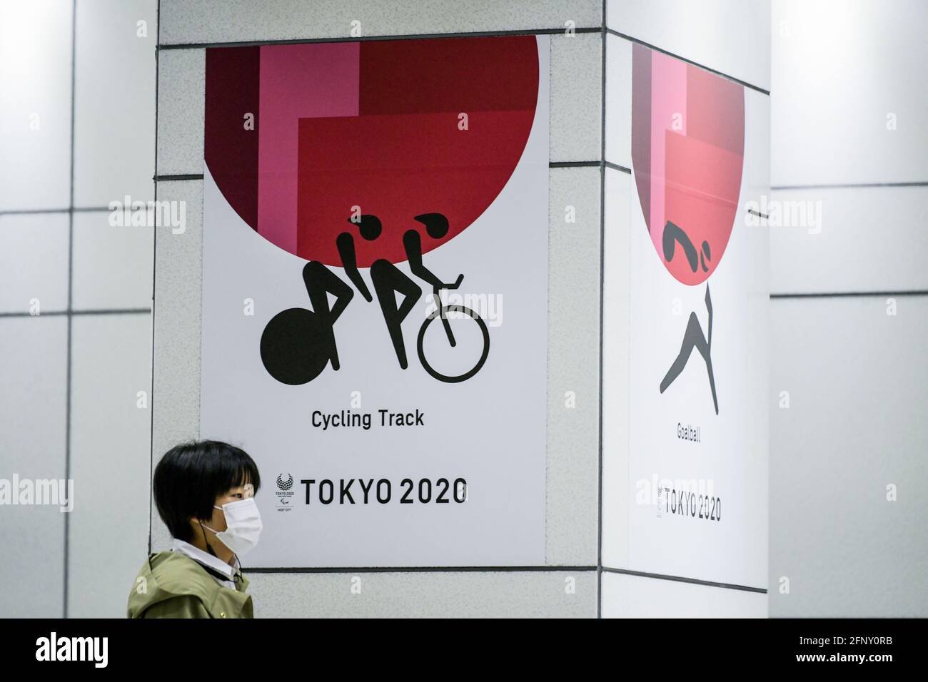A woman walks past Tokyo 2020 advertising posters at the Shinjuku Metro ...