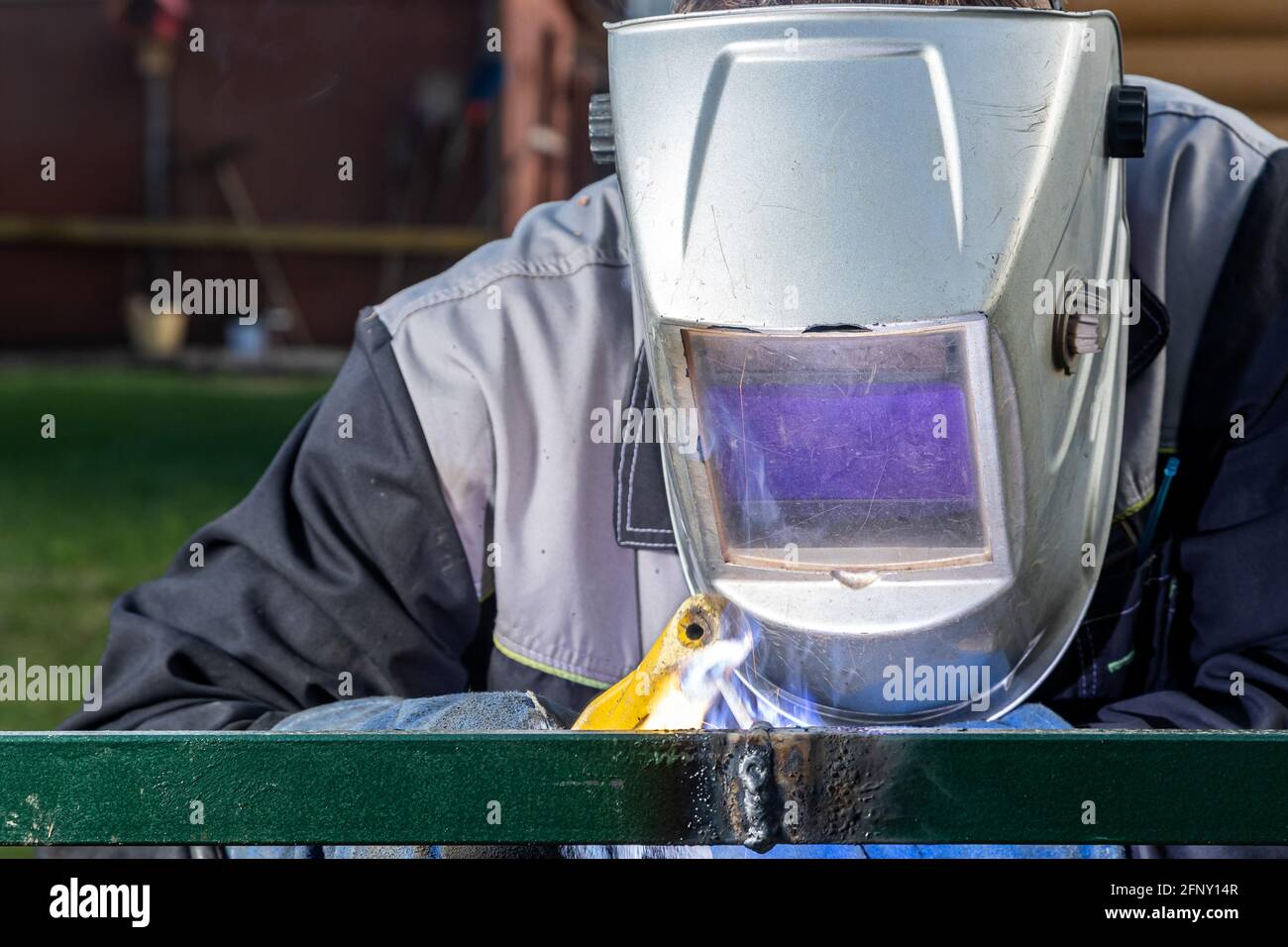 The welder welds a new metal frame for the fence around the house in ...