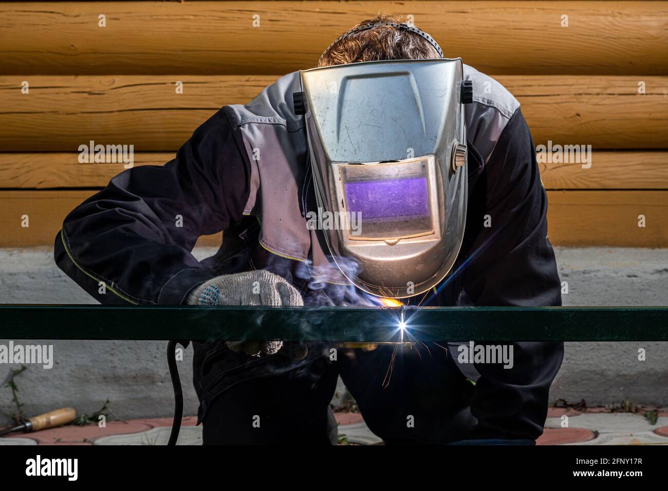 Worker male welder at a construction site welds a metal structure on a ...