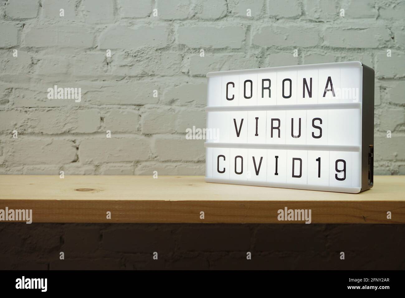 Corona Virus Covid-19 word in light box on wooden shelve and white ...