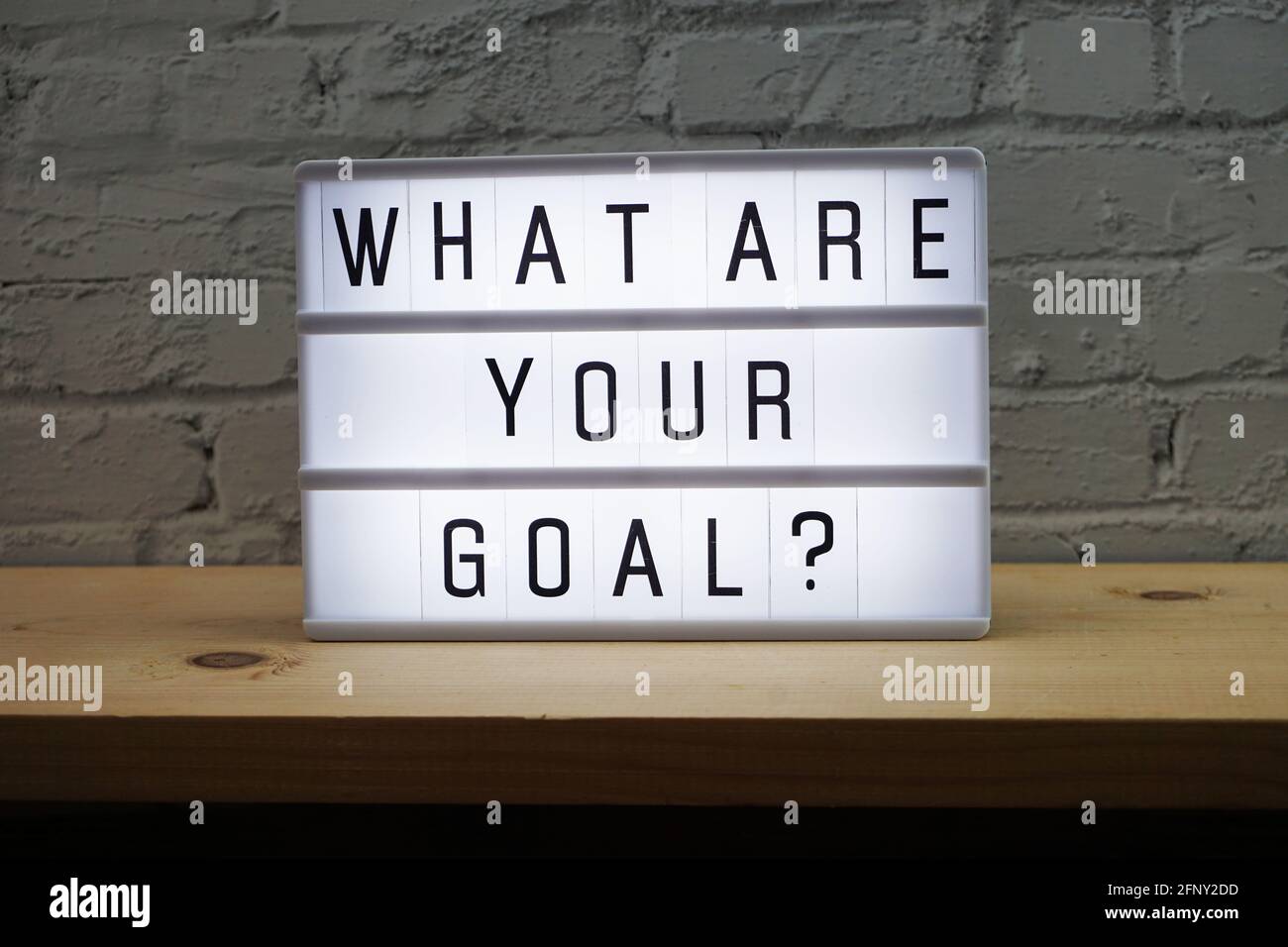 What Your Goal? word in light box on wooden shelf and white brick wall ...