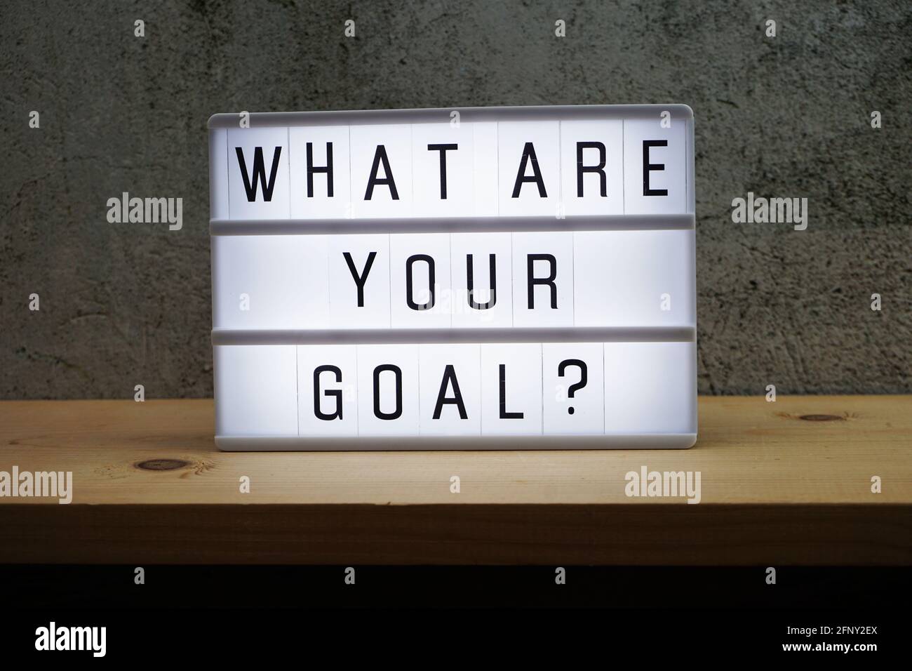 What Your Goal? word in light box on wooden shelf and concrete wall ...